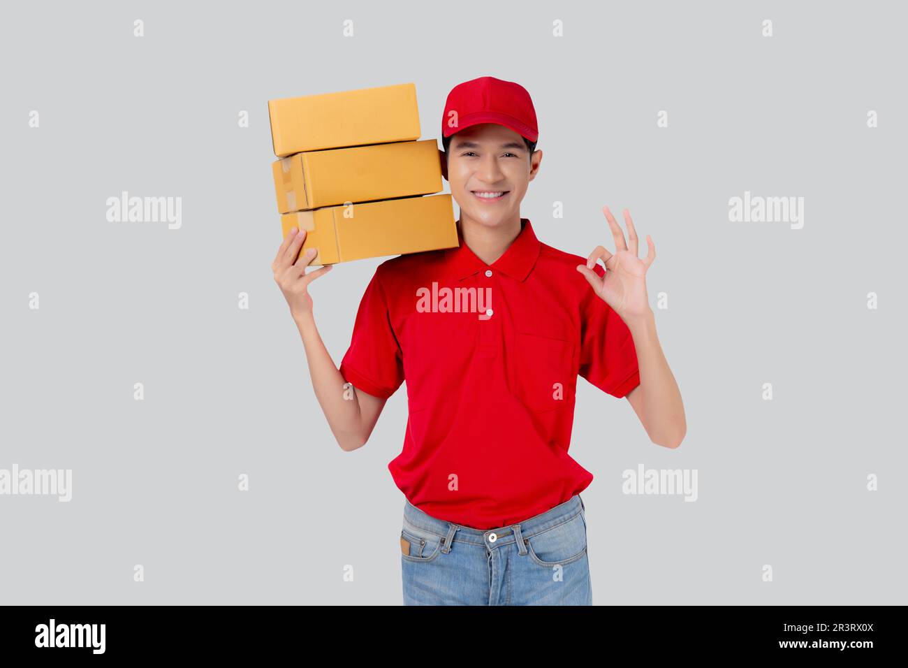 Young asian man in uniform red and cap standing carrying box stack and ...