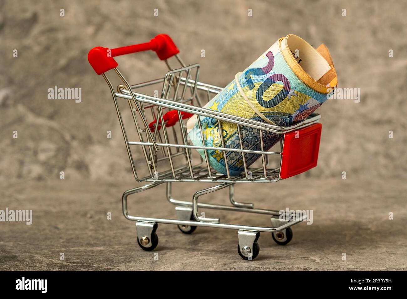 Shopping cart with a roll of euro banknote Stock Photo - Alamy