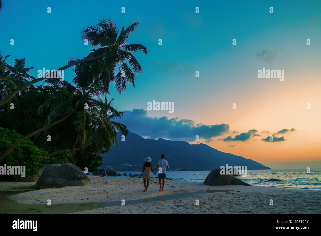 Couple of men and women watching sunset o a tropical beach at the ...