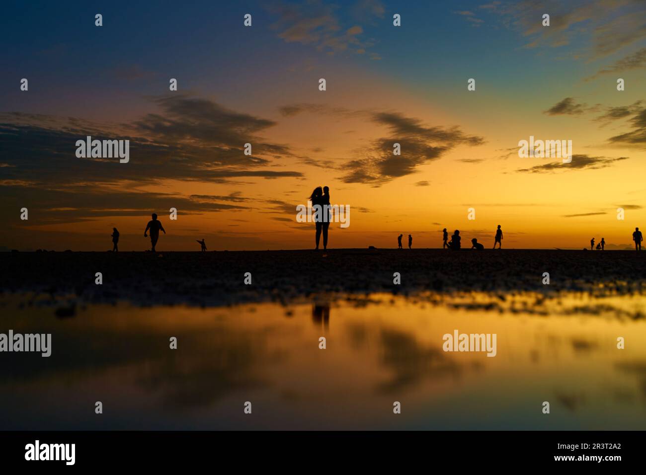 Silhouettes of people walking on the ocean floor after the evening tide ...