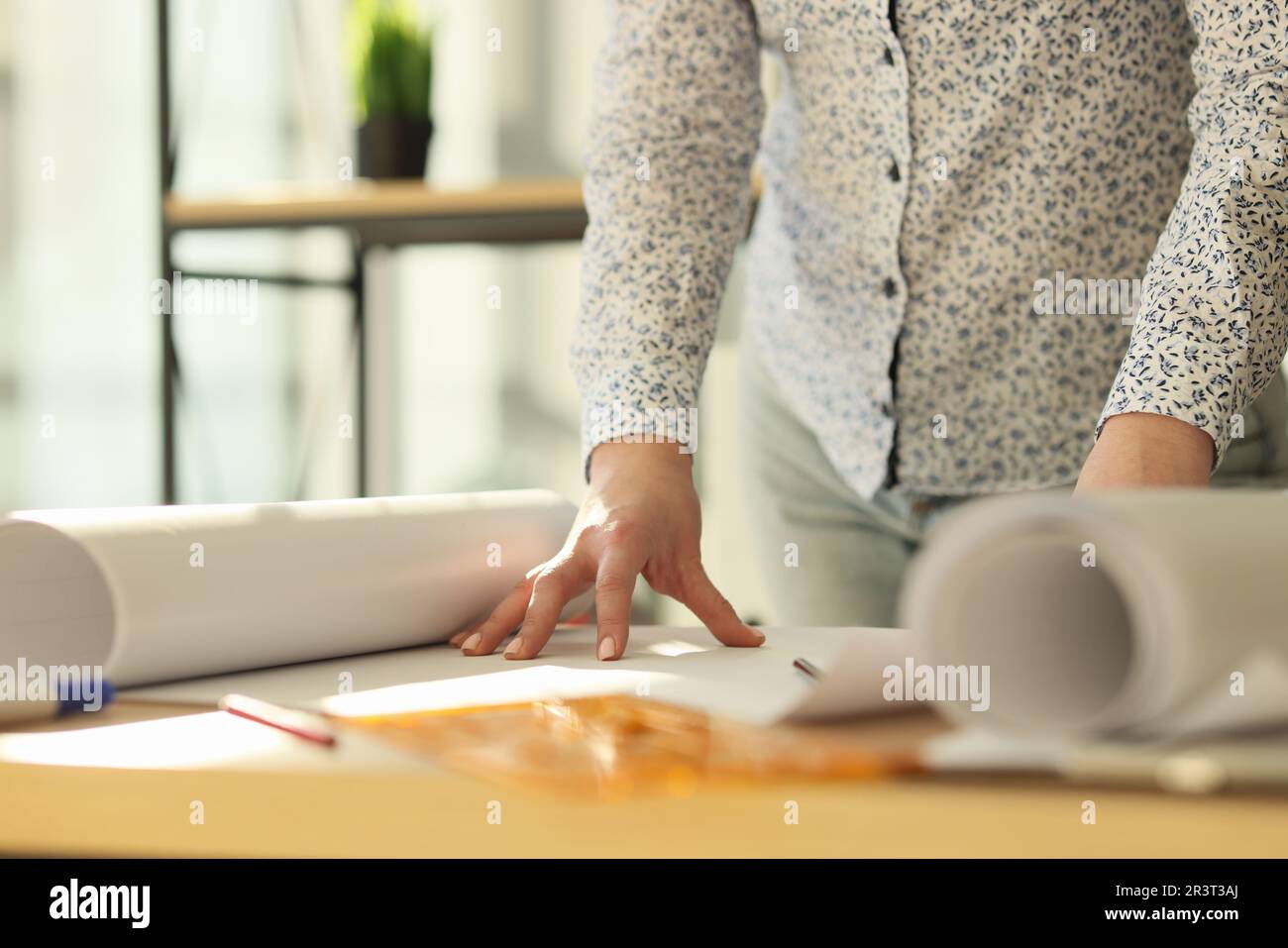 Female engineer unrolls large paper with building drawing Stock Photo ...
