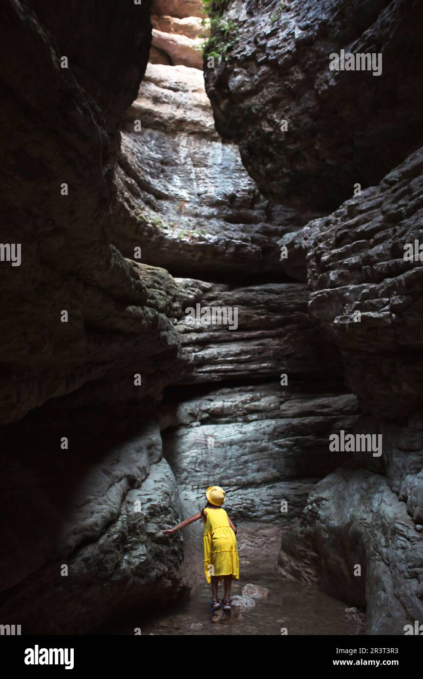 A tourist girl in a yellow dress in a high gorge in the mountains of ...