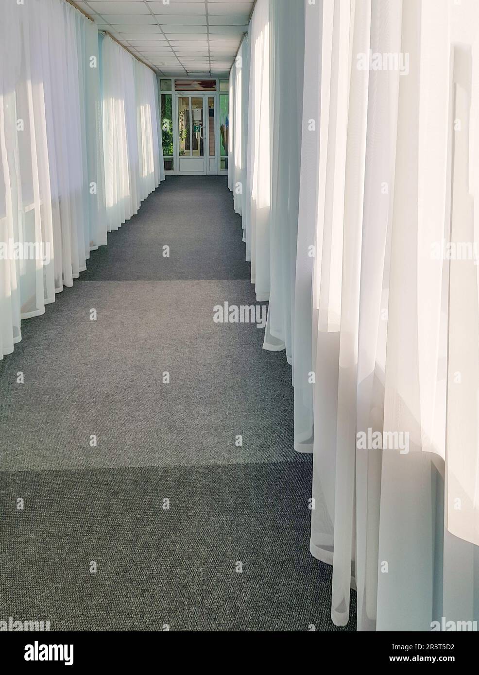 The prospect of a long hotel corridor with transparent curtains on ...