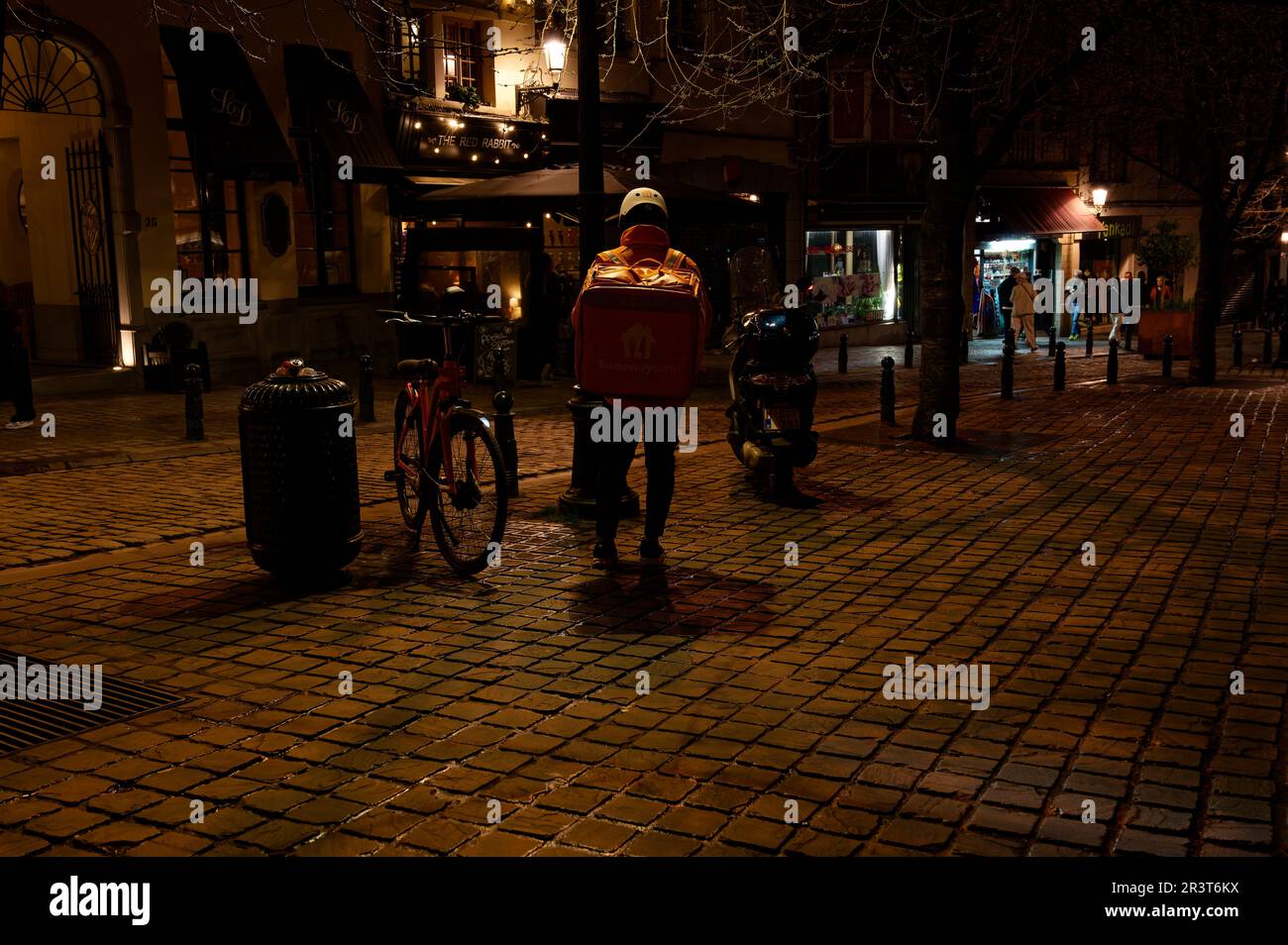 Courier for a food delivery service waiting in front of a restaurant at ...