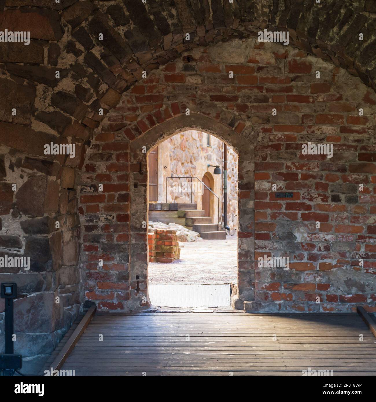 Arched doorway in stone and brick wall to the courtyard of medieval ...