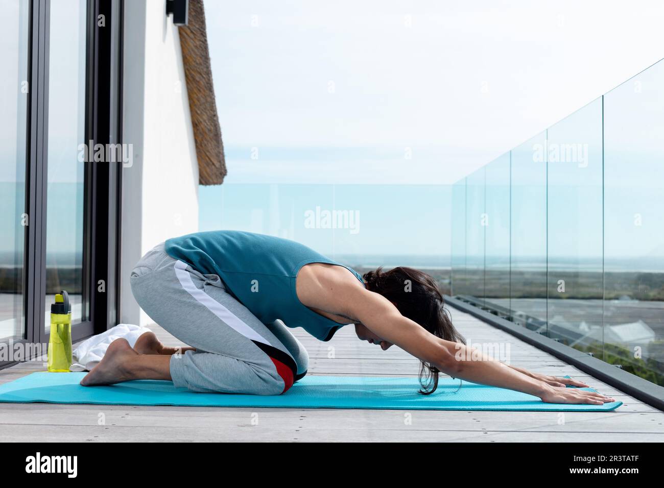 Happy biracial man doing yoga, stretching on balcony Stock Photo - Alamy