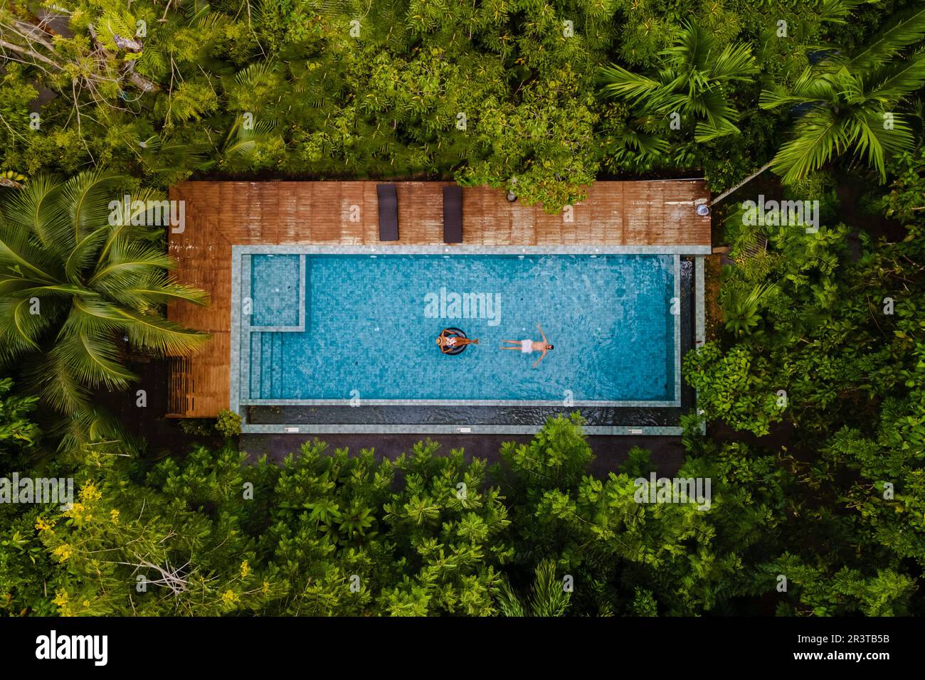 Drone view of a swimming pool in the jungle , couple men and women in a ...