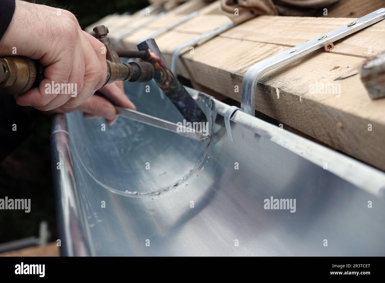 Roofer soldering the seam of a gutter Stock Photo - Alamy