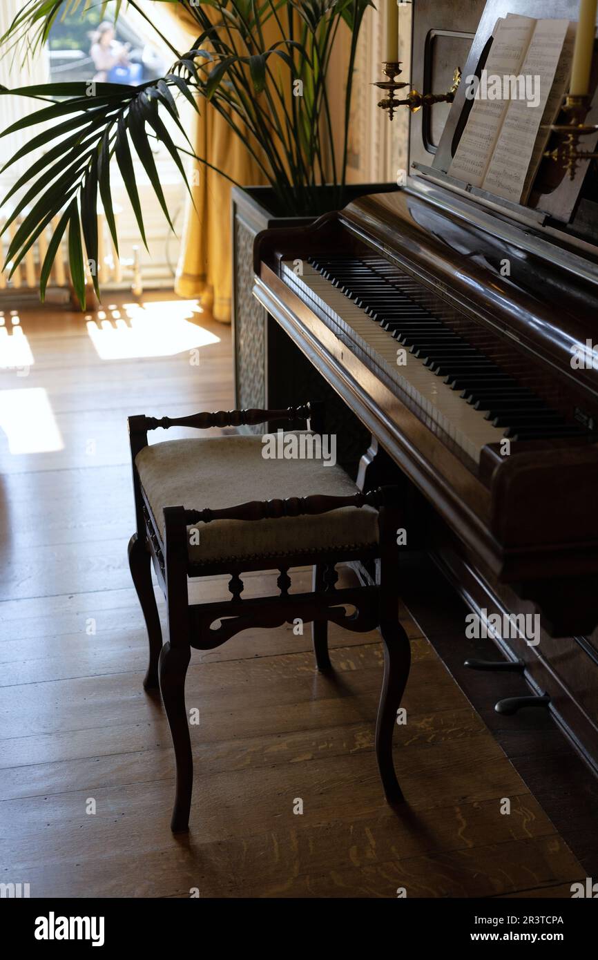 An old antique upright next to a window with a potted palm plant Stock ...