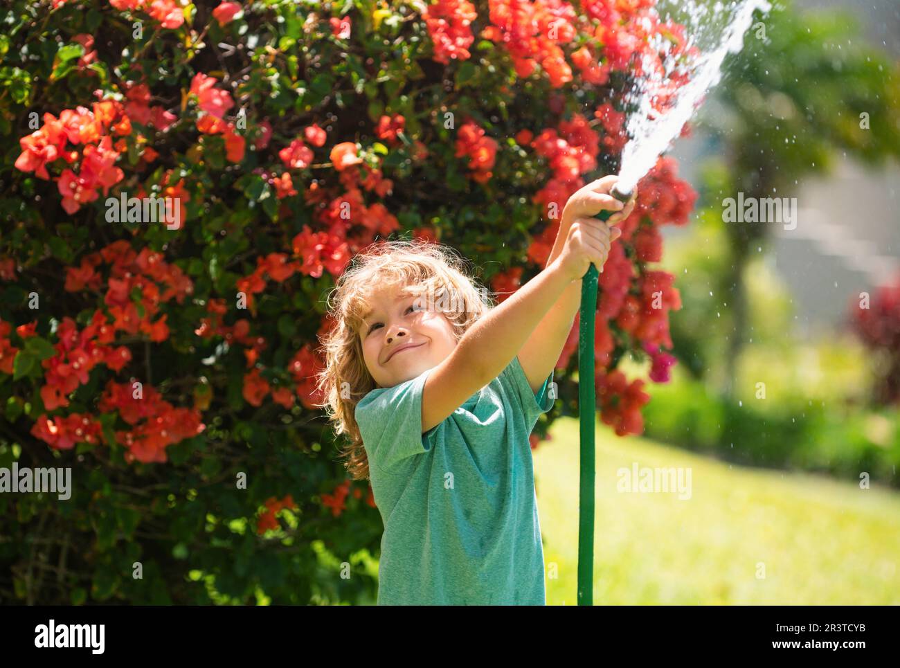 Child playing with garden hose in backyard. Funny excited kid having ...
