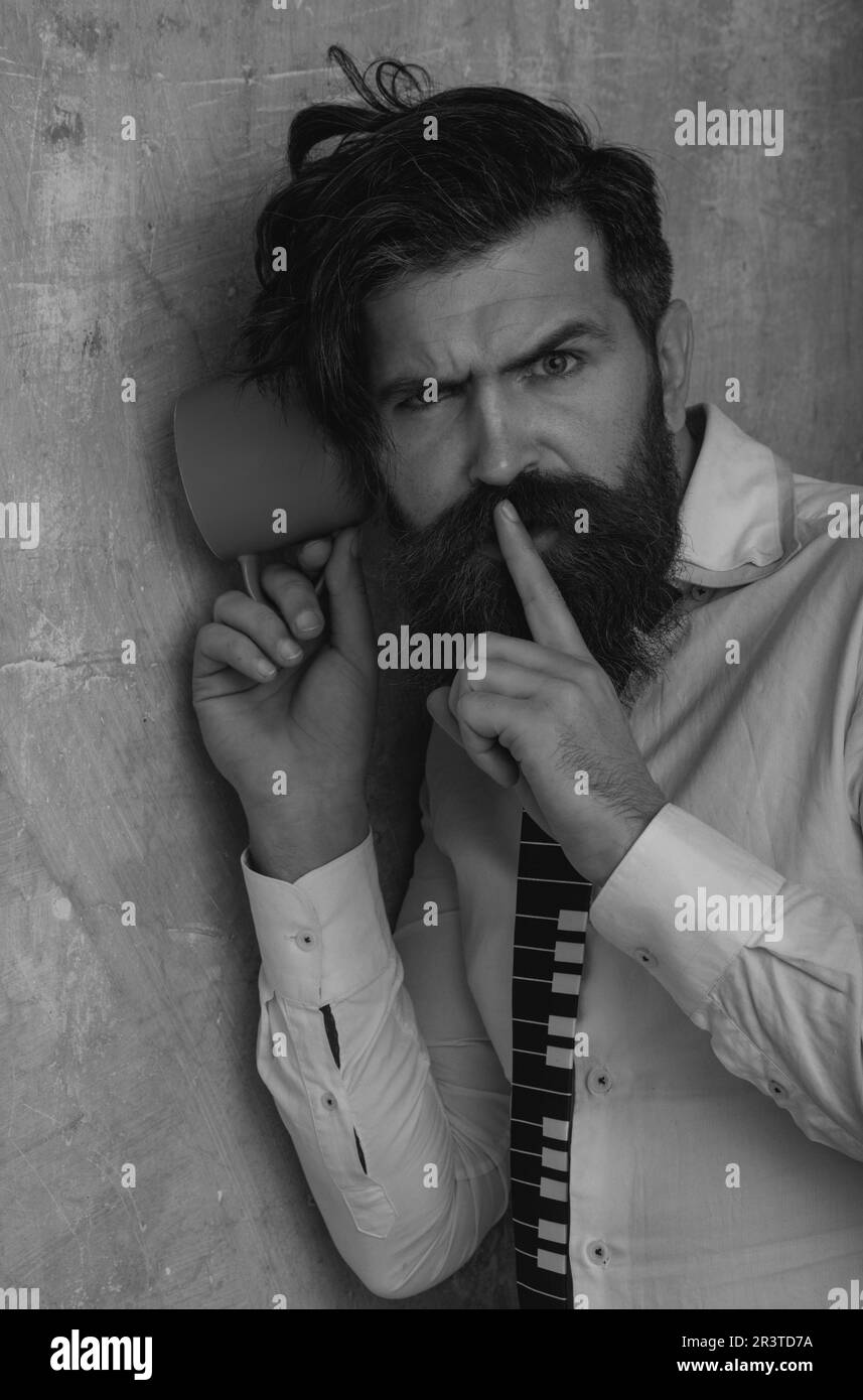 Man listening through the wall with the cup. Secrets and gossip concept. Curious guy overhearing ...