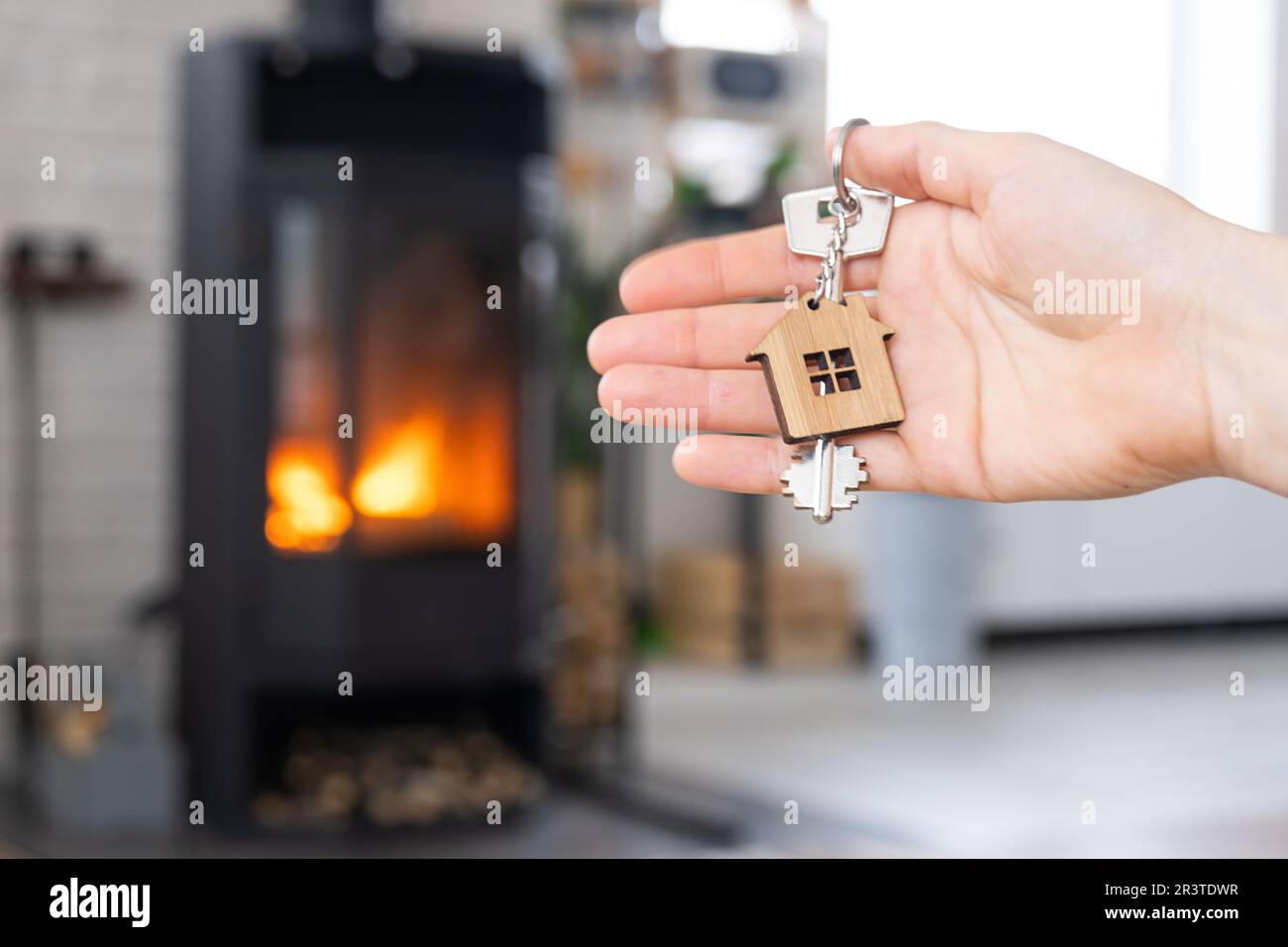 Key to house with keychain in hand owner against of fireplace stove ...