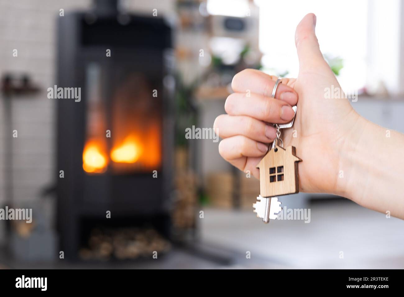 Key to house with keychain in hand owner against of fireplace stove ...