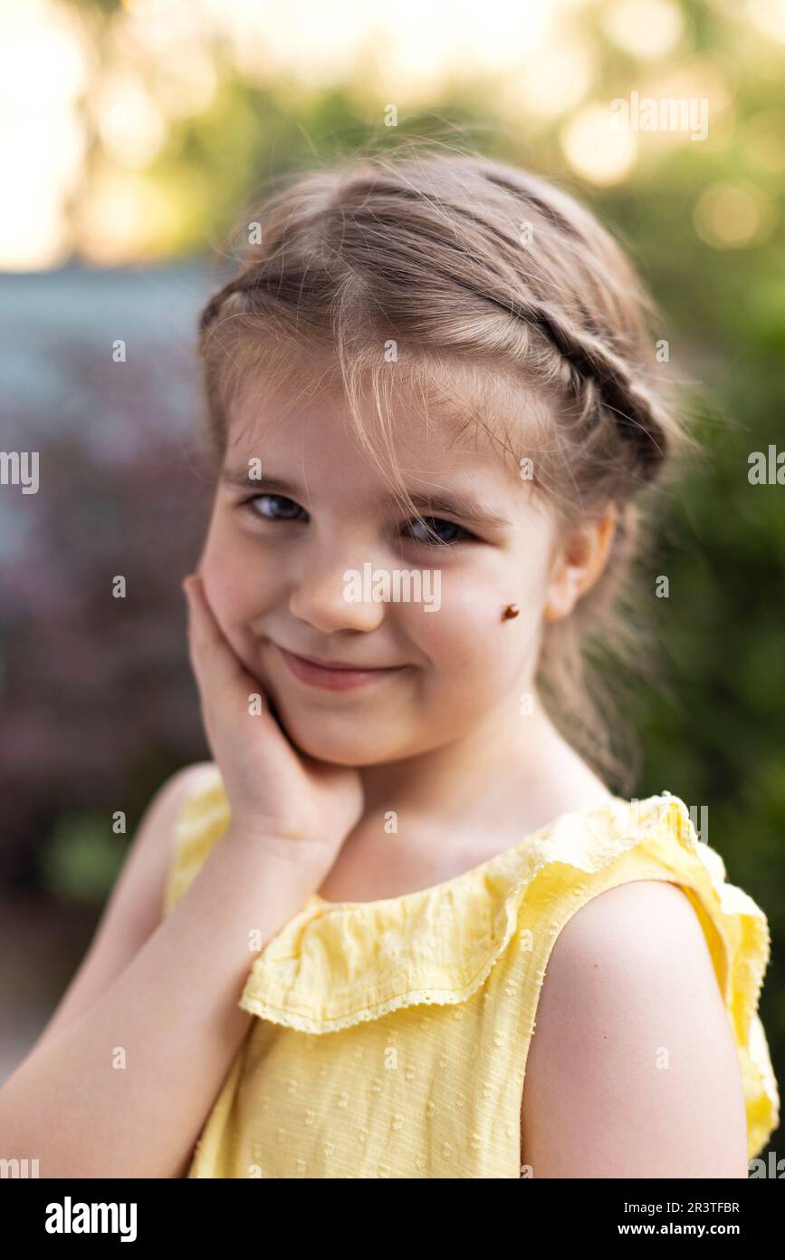 Portrait of the little girl holding hand on one check and have red ...