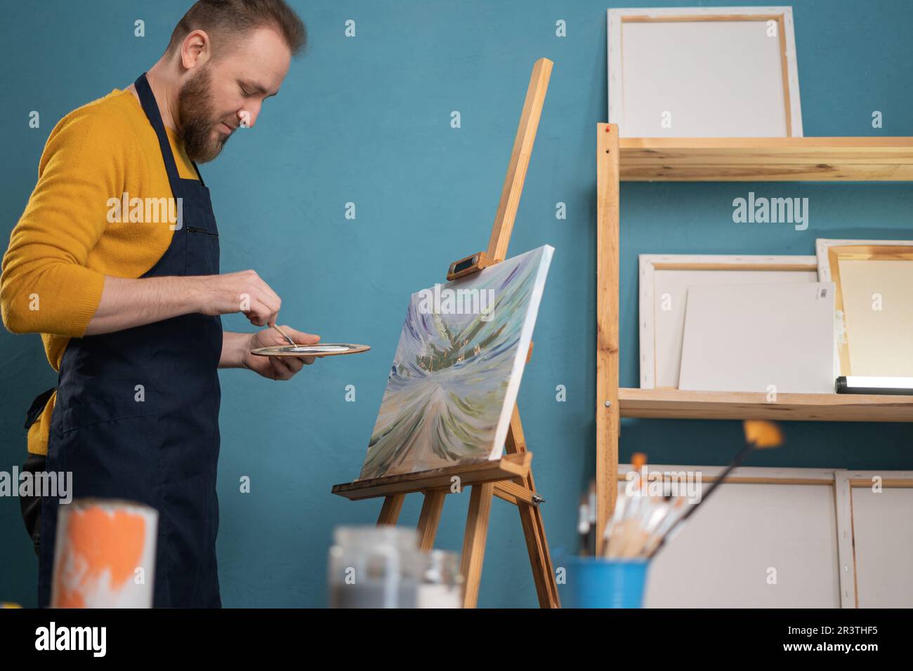 Man painter standing in front of the canvas and drawing. Artist using ...