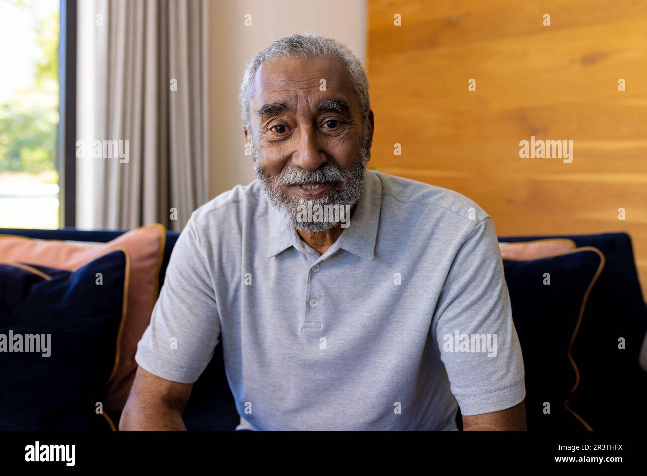 Happy senior biracial man with beard making video call sitting on sofa ...