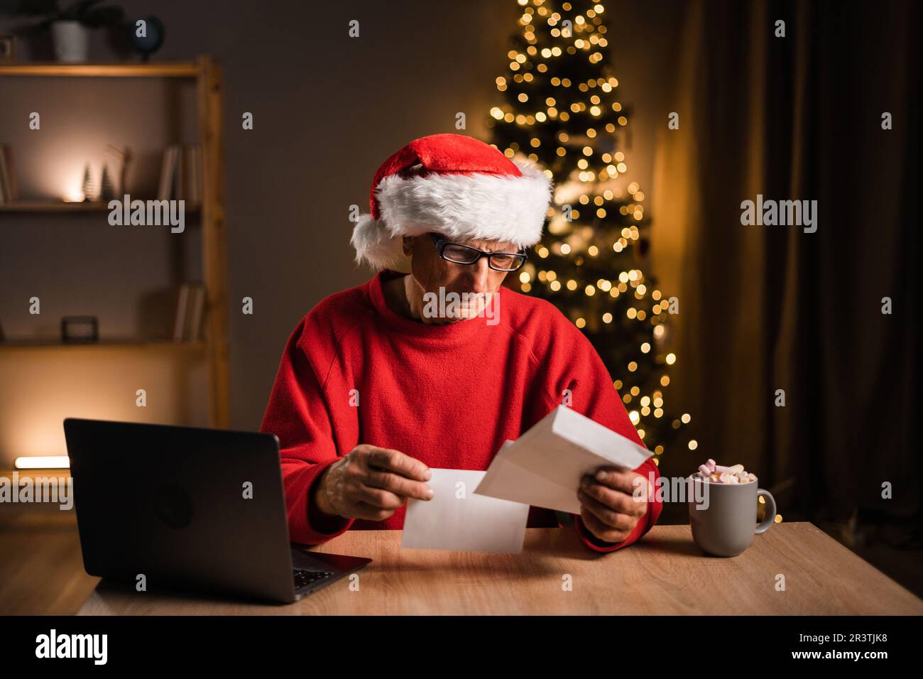 Senior man in Santa hat keeping an envelope with Christmas greeting ...