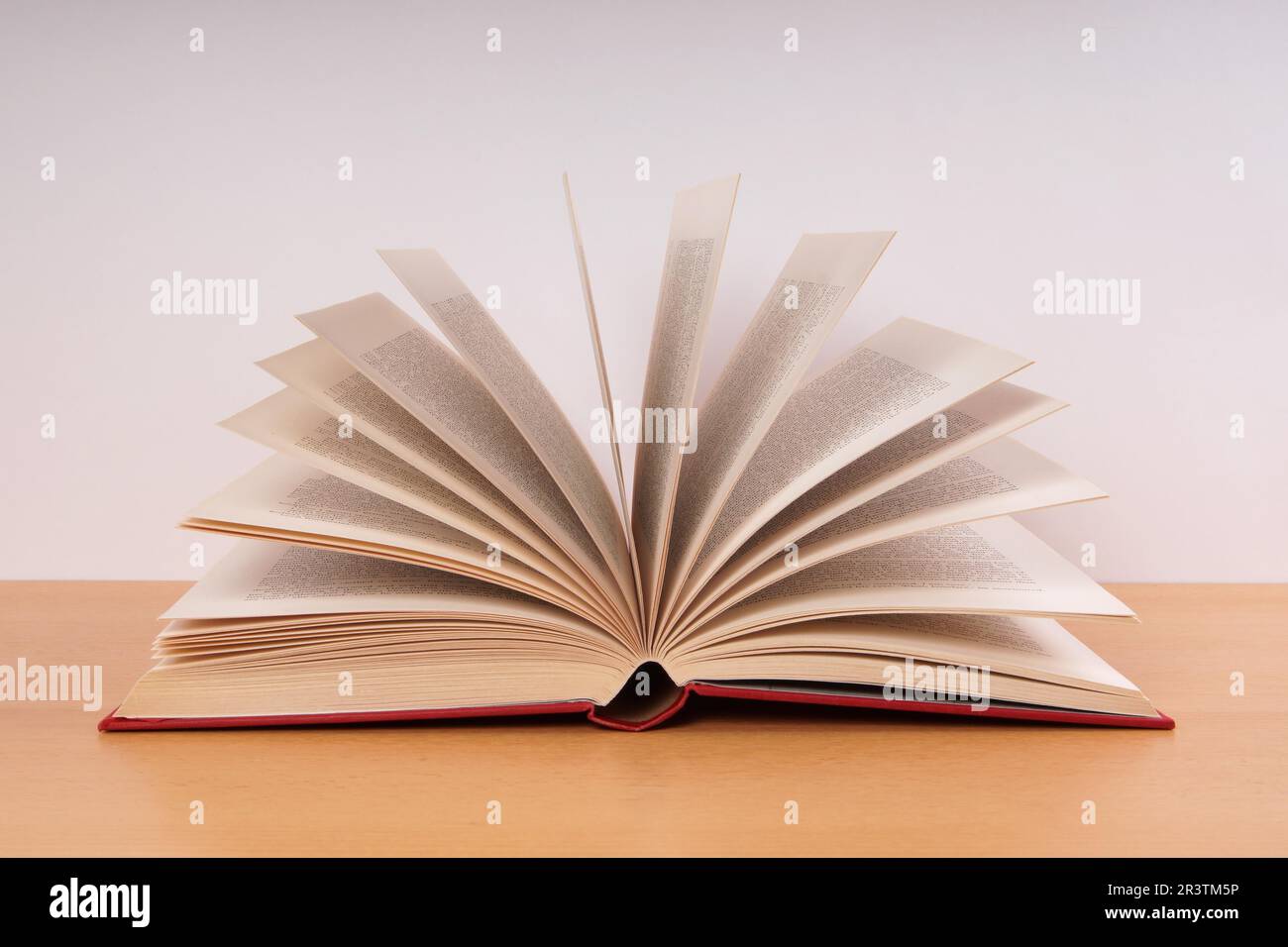 open hardcover book with turning pages in fan shape on desk Stock Photo ...