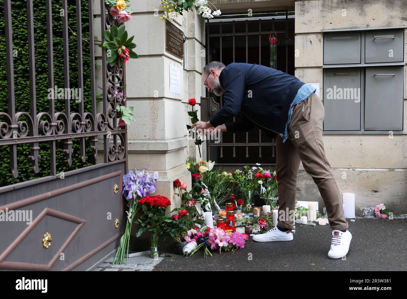 A man places a message and a red rose at the gate of the house of late ...