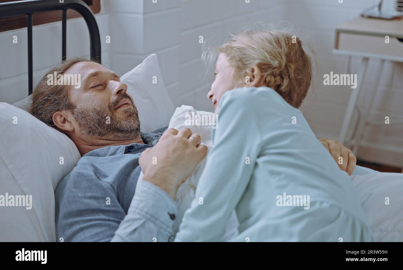 Daughter wakes up father at the bed in the morning Stock Photo - Alamy