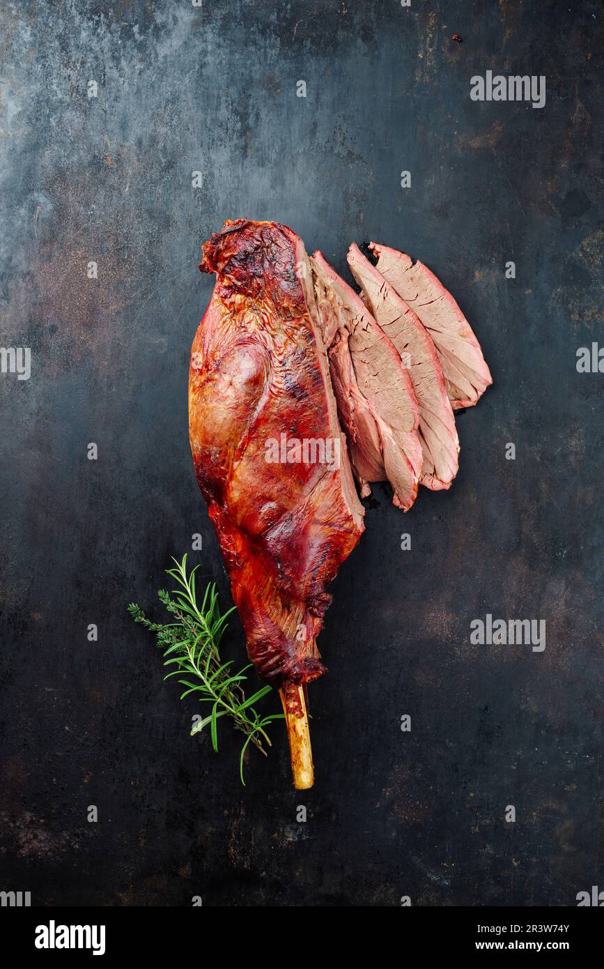 Traditional barbecue leg of venison sliced and served with herbs as top ...