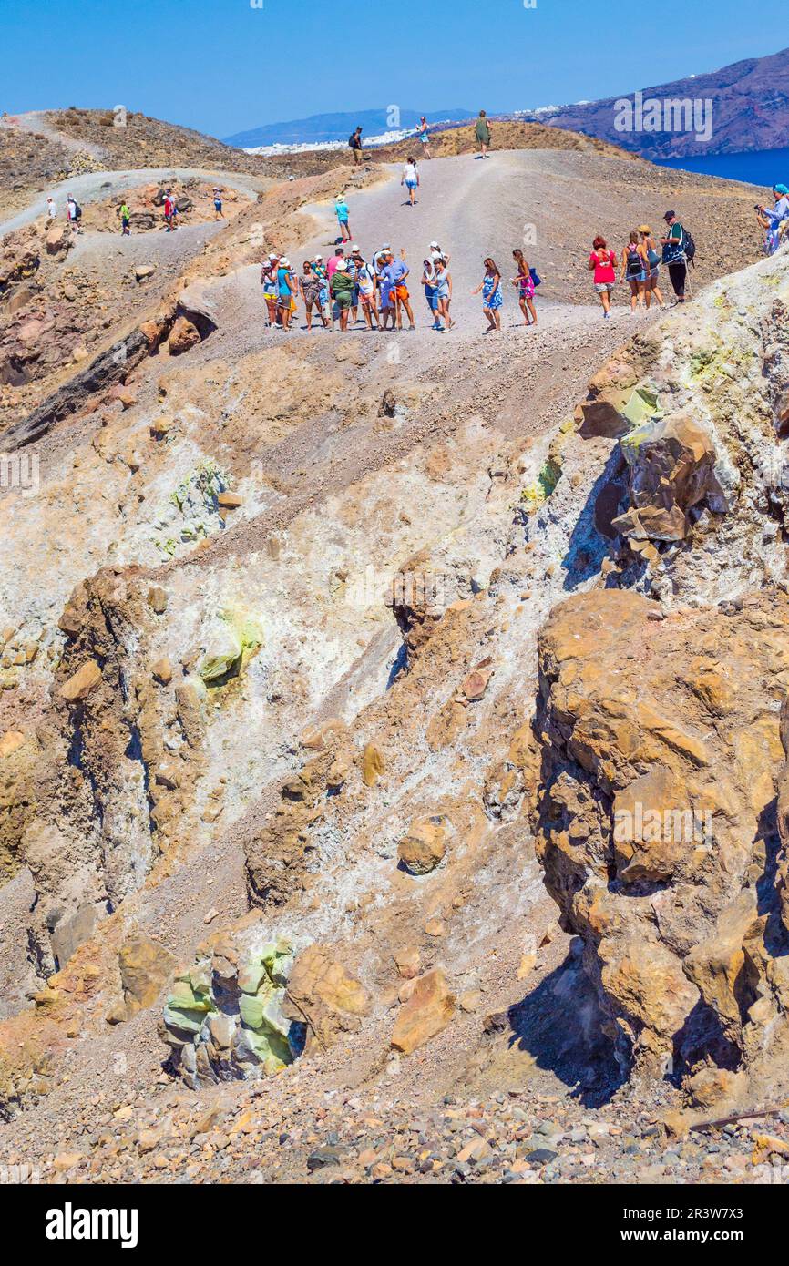 Tourists sightseeing the active volcano- highlight of Santorini and ...