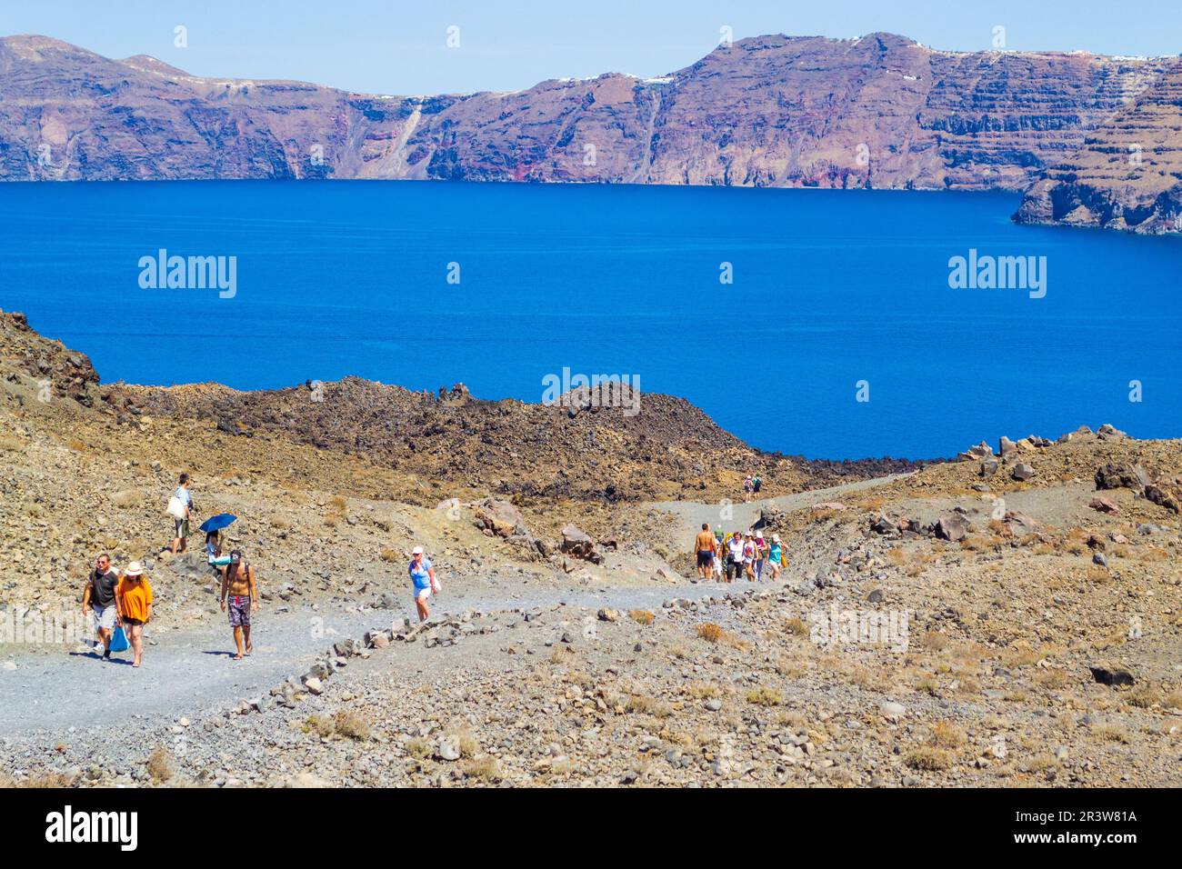 Tourists hiking to the active volcano- highlight of Santorini and ...