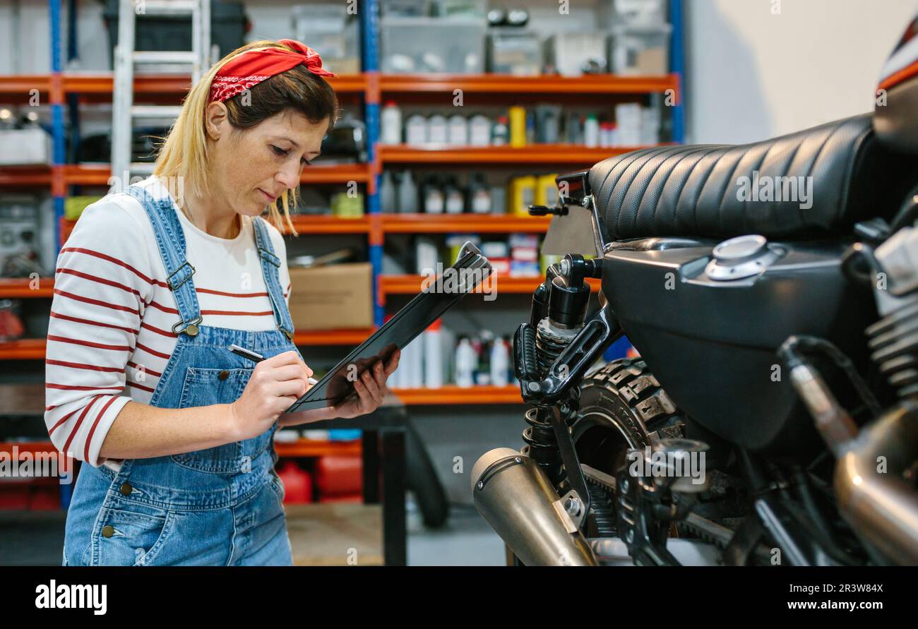 Mechanic woman checking motorcycle on factory Stock Photo - Alamy