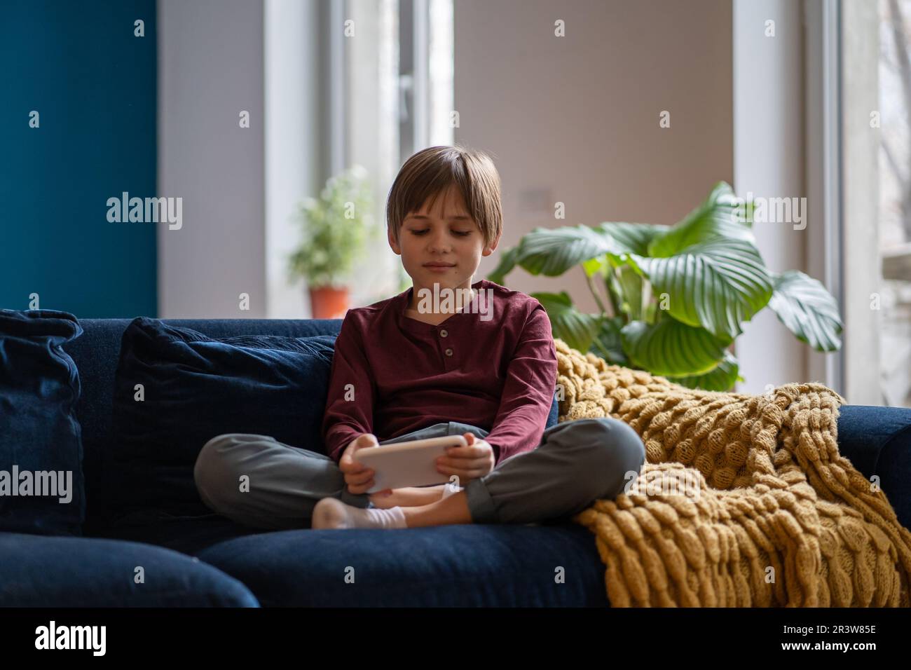Little boy kid playing mobile games staring at screen while resting on ...