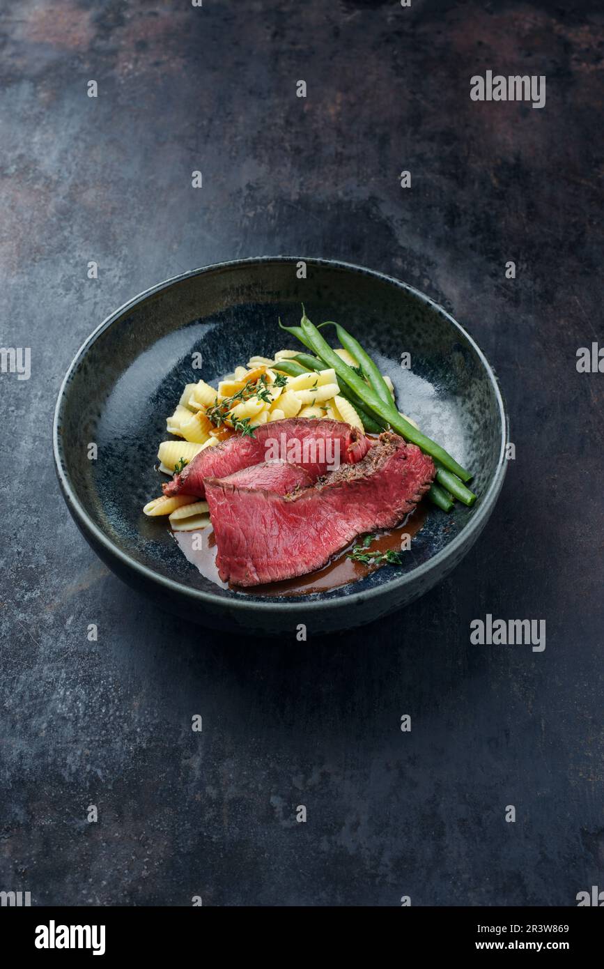 Traditional Italian chianina sliced roast beef with gnocchetti sardi ...