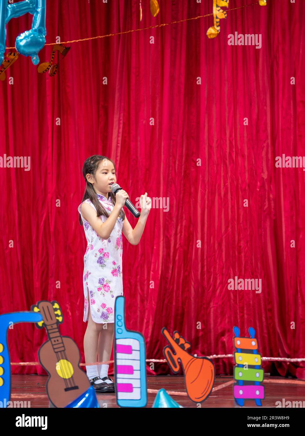 The Asian kid girl sing a song on stage at her school activity day ...