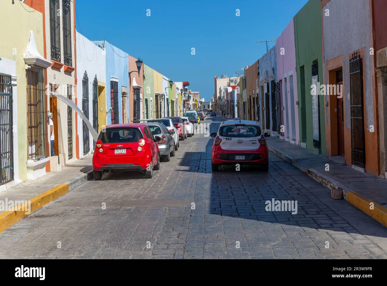 Street with cars parked and taxi, colourful Spanish colonial buildings ...