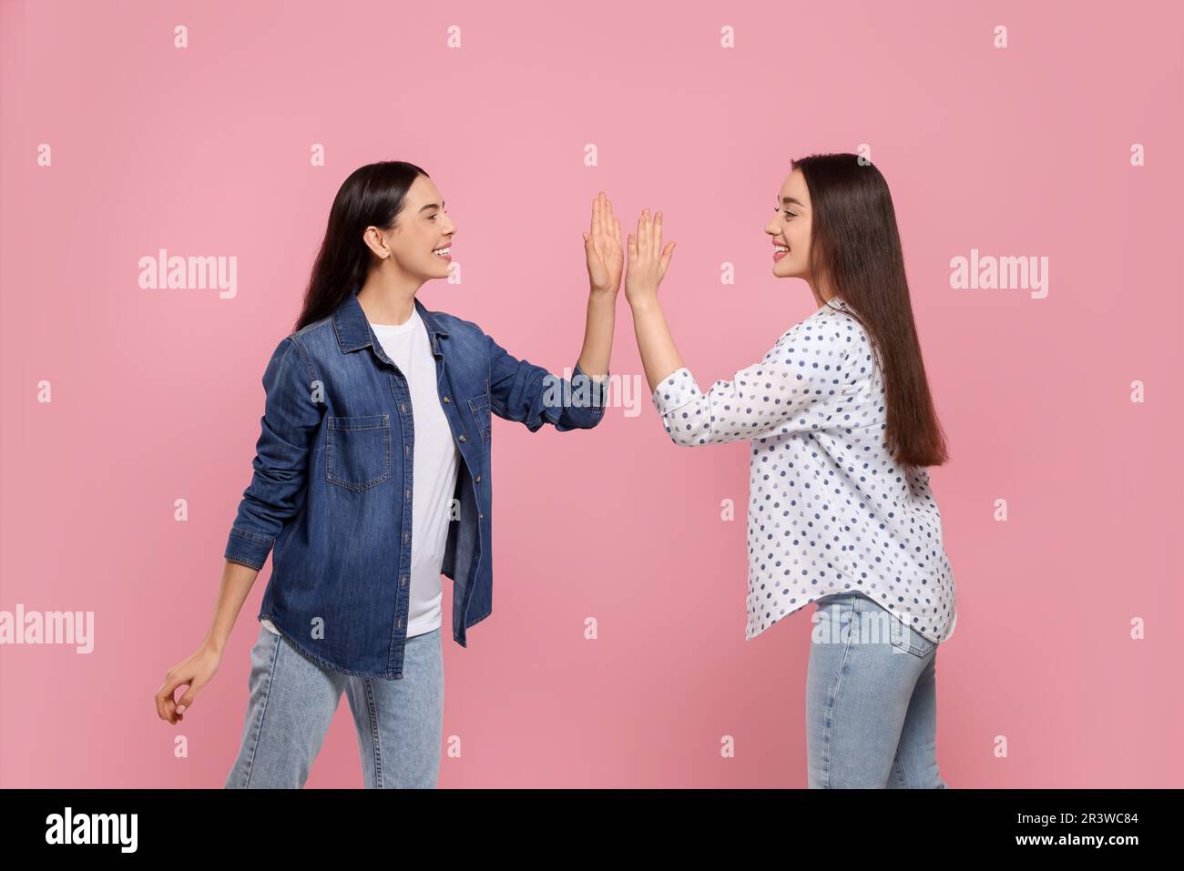 Women giving high five on pink background Stock Photo - Alamy