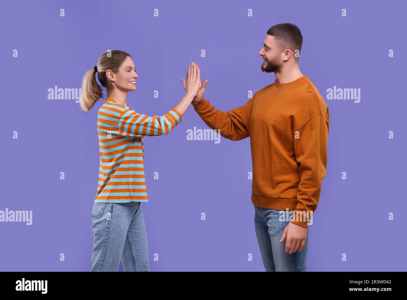 Happy couple giving high five on purple background Stock Photo - Alamy
