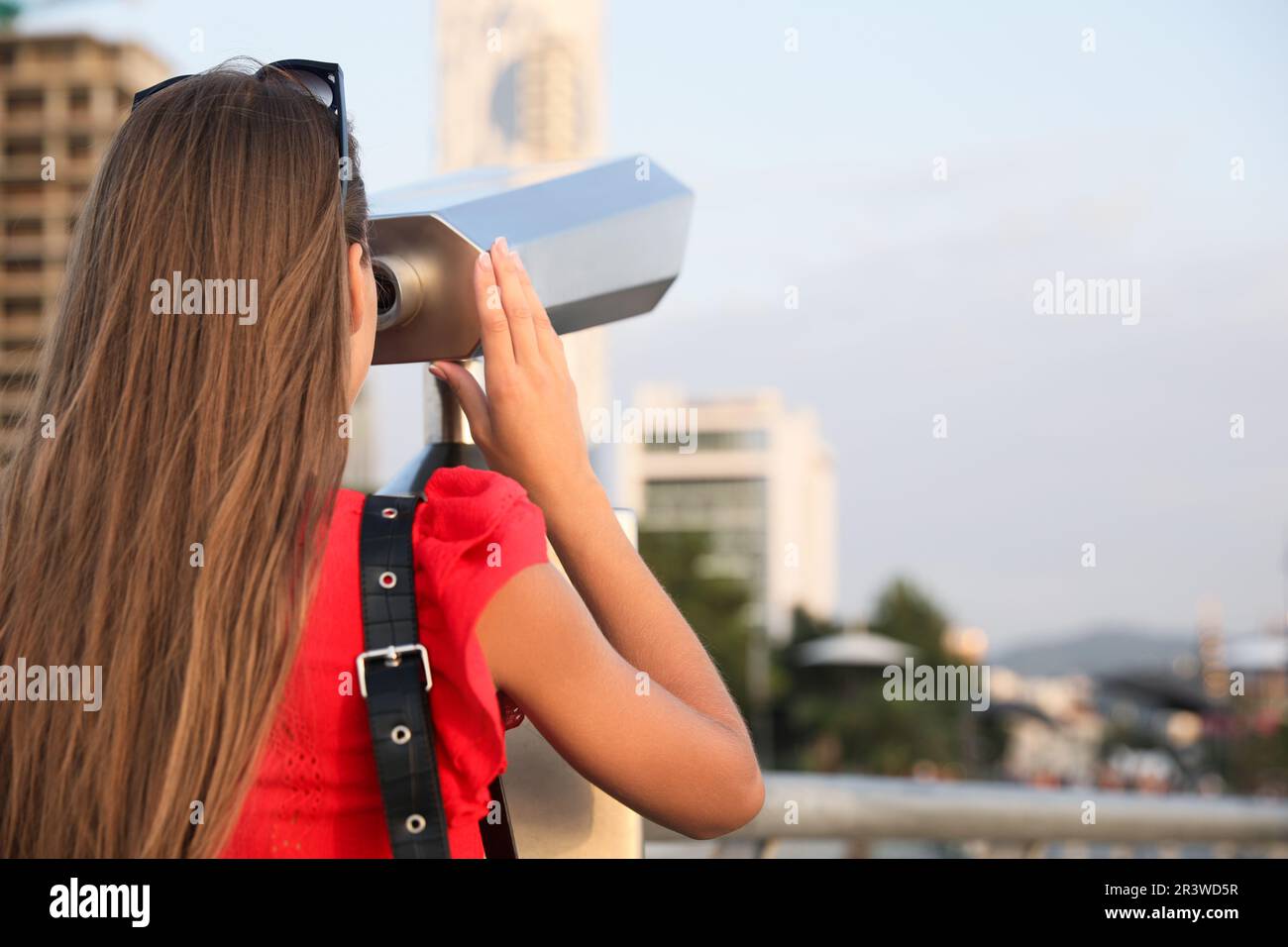 Young woman looking through tourist viewing machine at observation deck ...