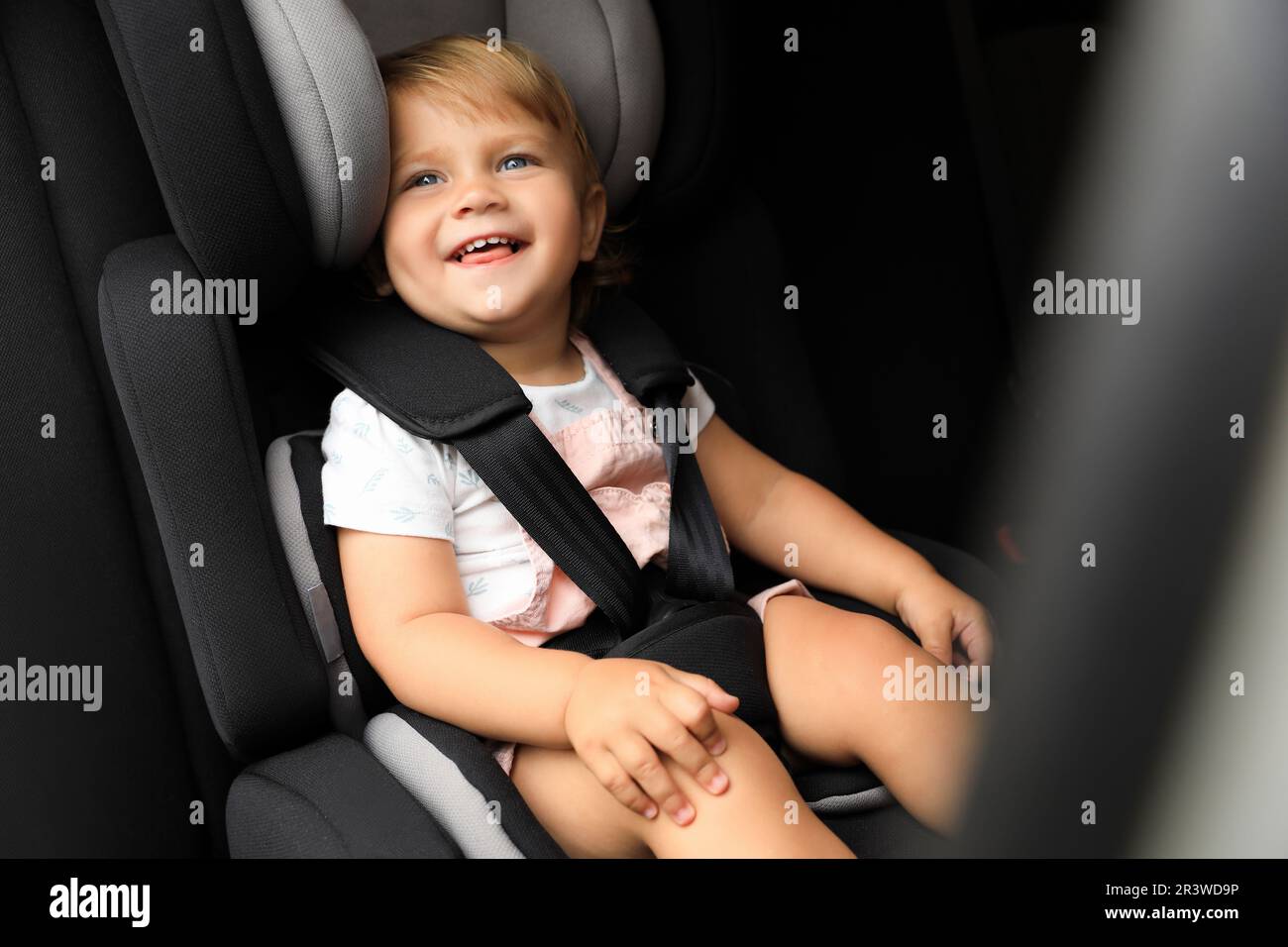 Cute little girl sitting in child safety seat inside car Stock Photo ...