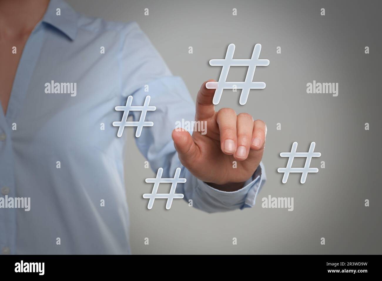 Hashtag concept. Woman pointing at sign on light grey background ...