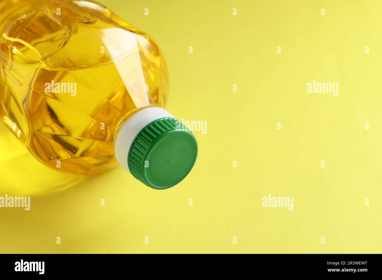 Plastic bottle of cooking oil on yellow background. Space for text ...