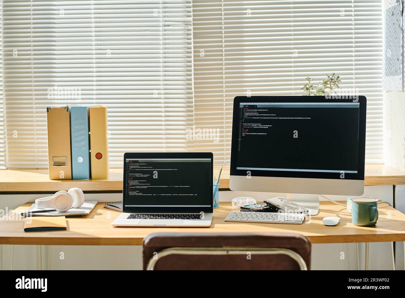 Horizontal image of computers with security codes on the screen standing on workplace of ...