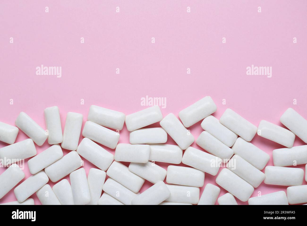 Tasty white chewing gums on pale pink background, flat lay. Space for ...