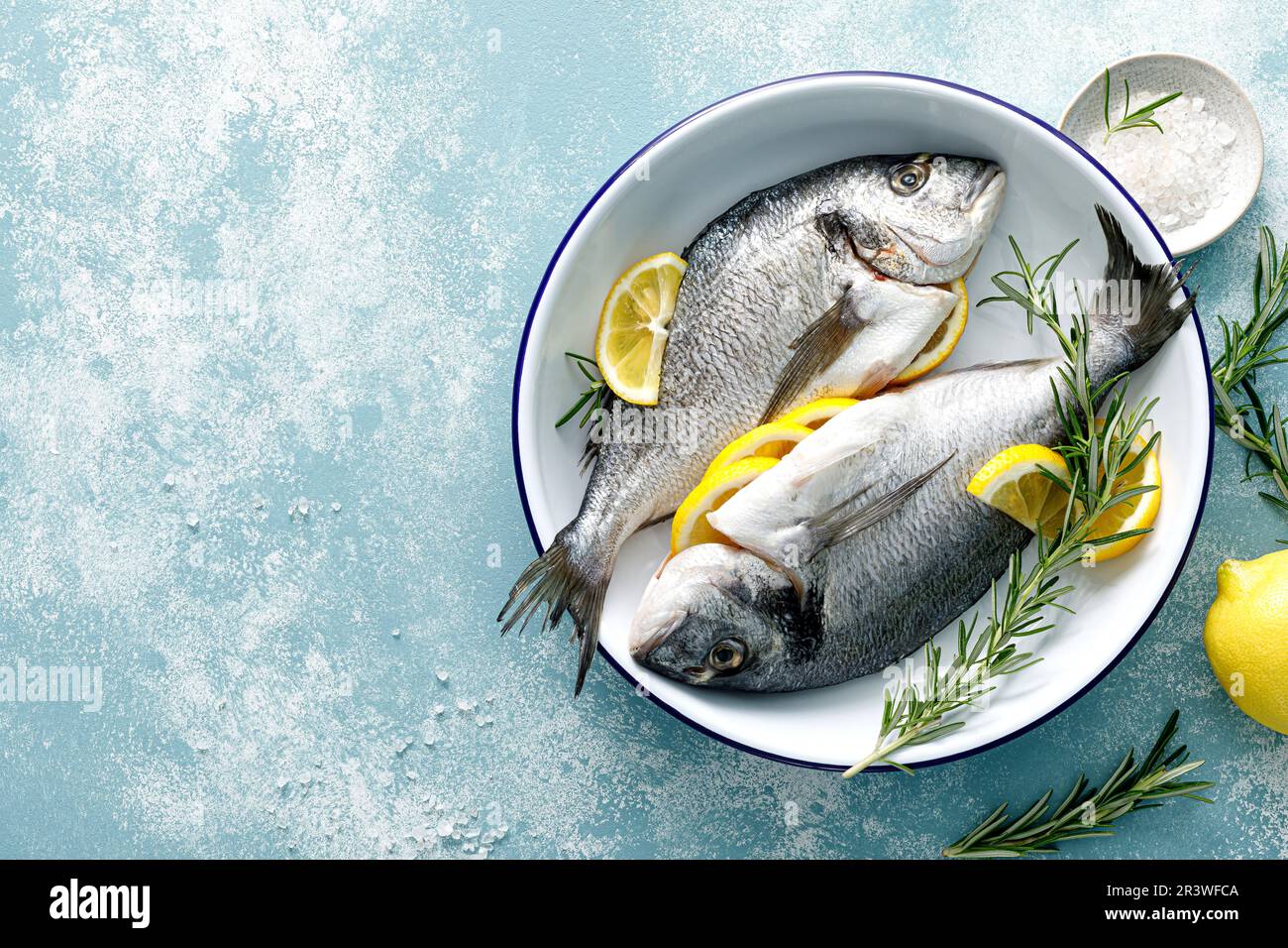 Fresh raw dorado fish cooking with lemon and rosemary. Sea bream ...