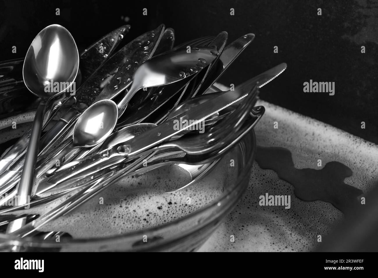 Washing silver spoons, forks and knives in kitchen sink with foam ...