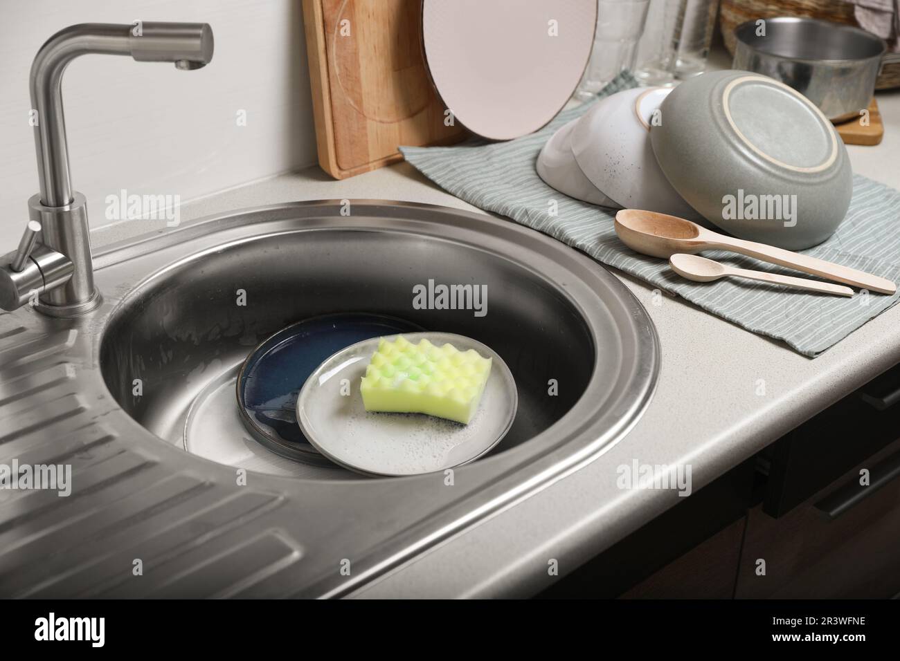 Washing plates and sponge in kitchen sink Stock Photo - Alamy