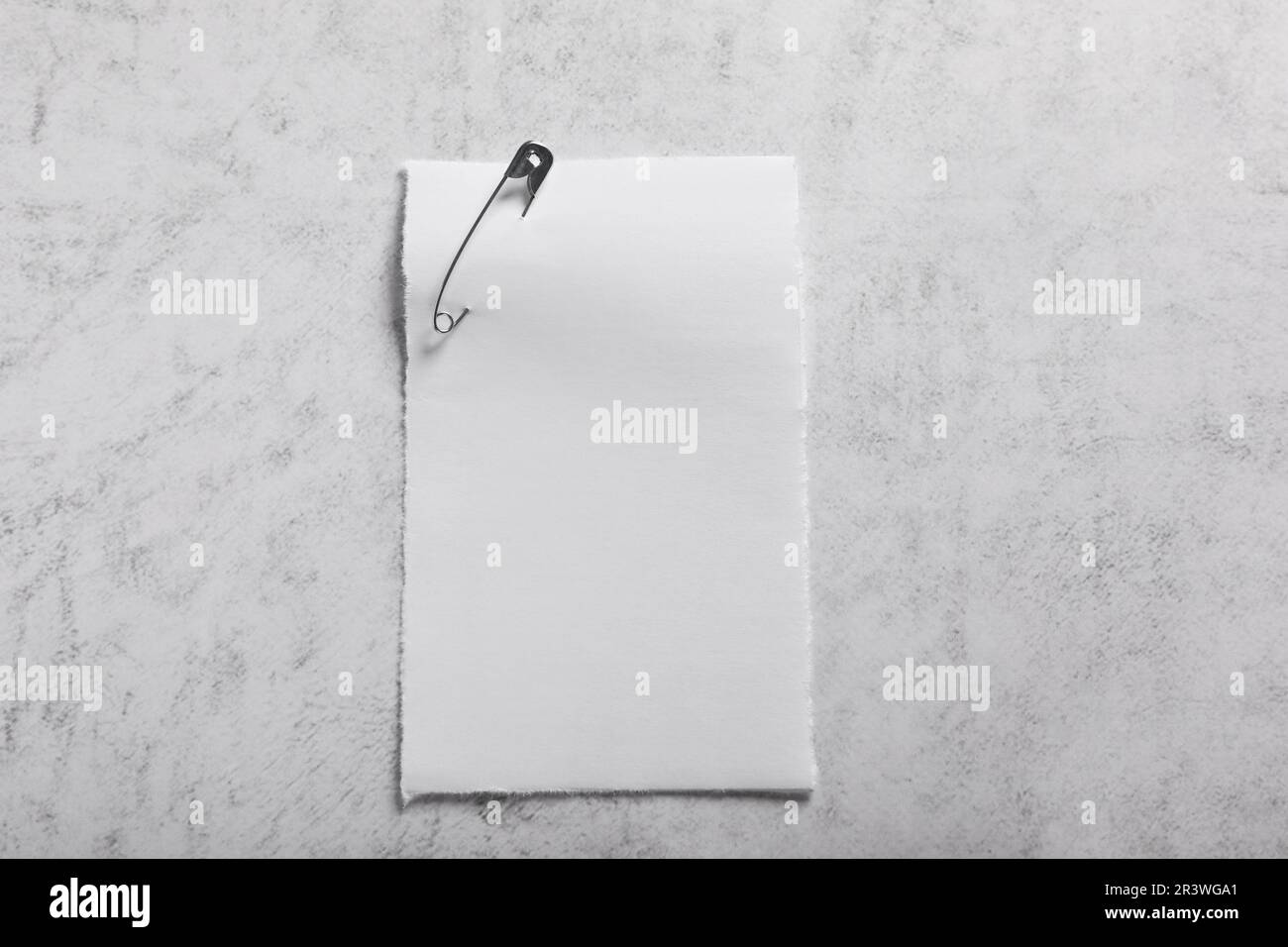 Sheet of paper attached with safety pin on grey textured background ...