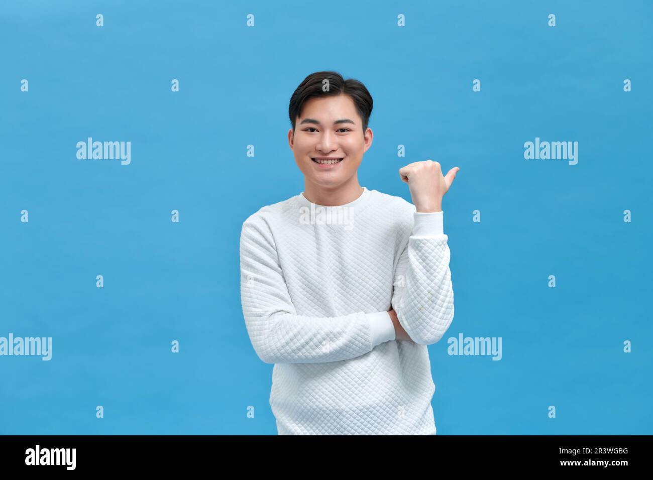 Young handsome man pointing to the back behind with hand and thumbs up ...