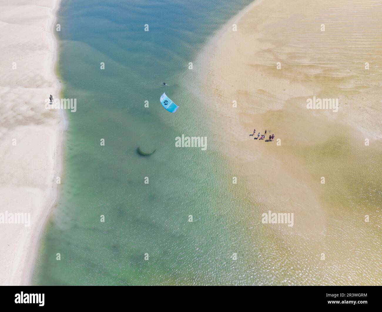 Aerial view of a kite surfer over a white sandy beach and tidal pool at ...