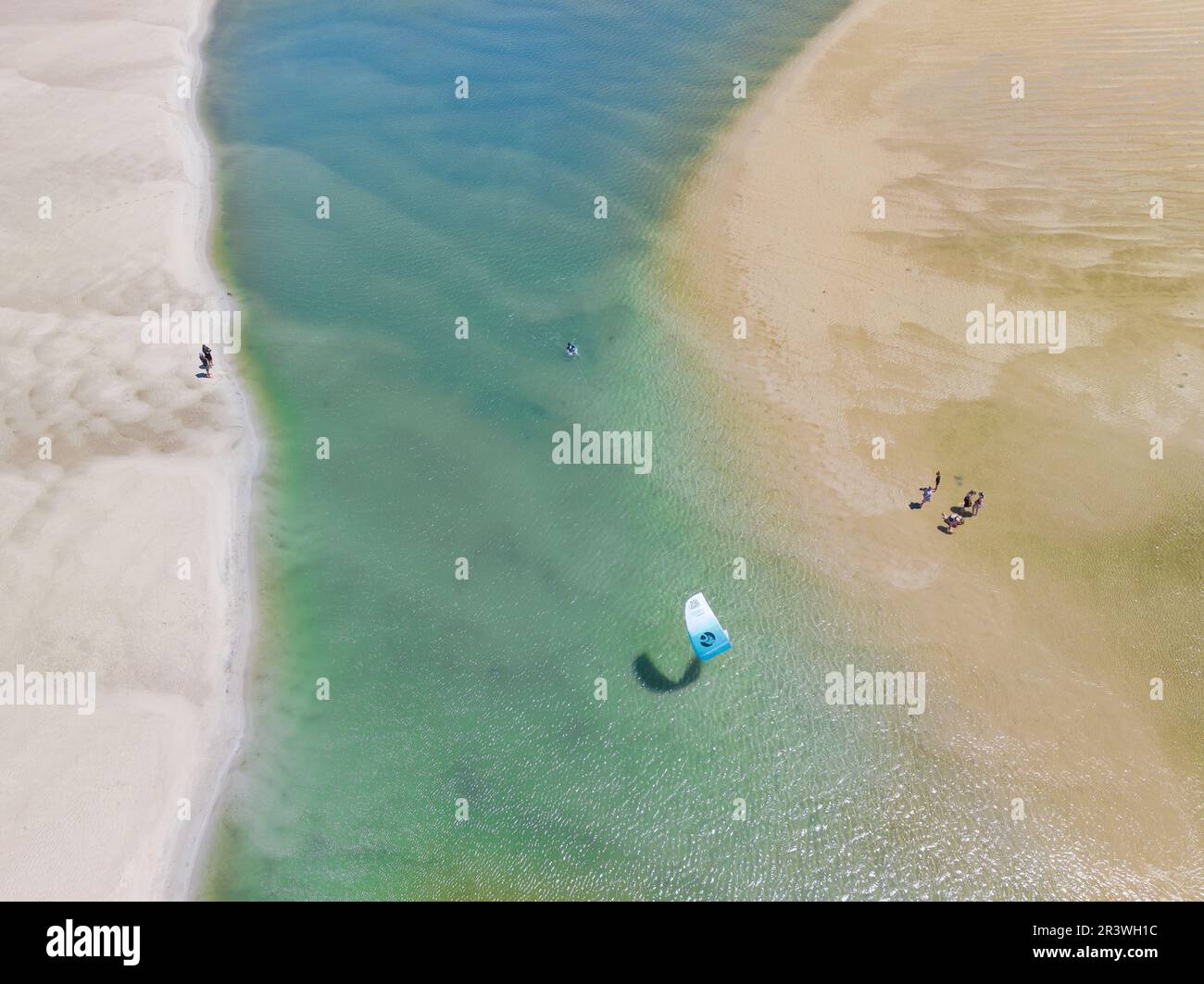 Aerial view of a kite surfer over a white sandy beach and tidal pool at ...