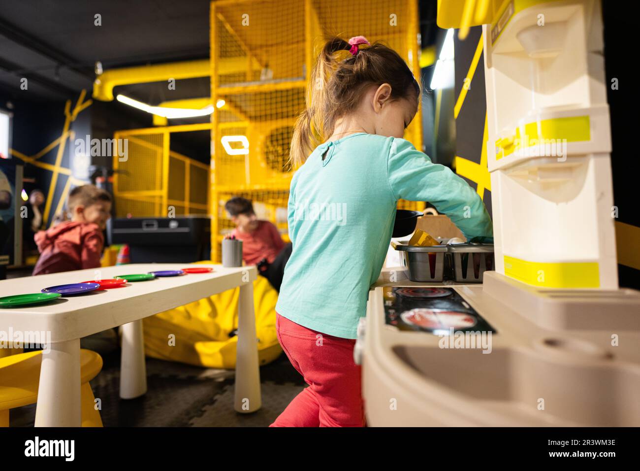 Baby girl playing in kids kitchen at children play center Stock Photo ...
