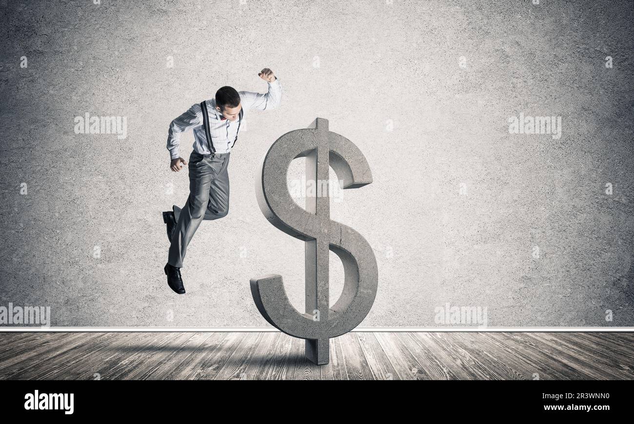 Determined banker man in empty concrete room breaking dollar figure ...