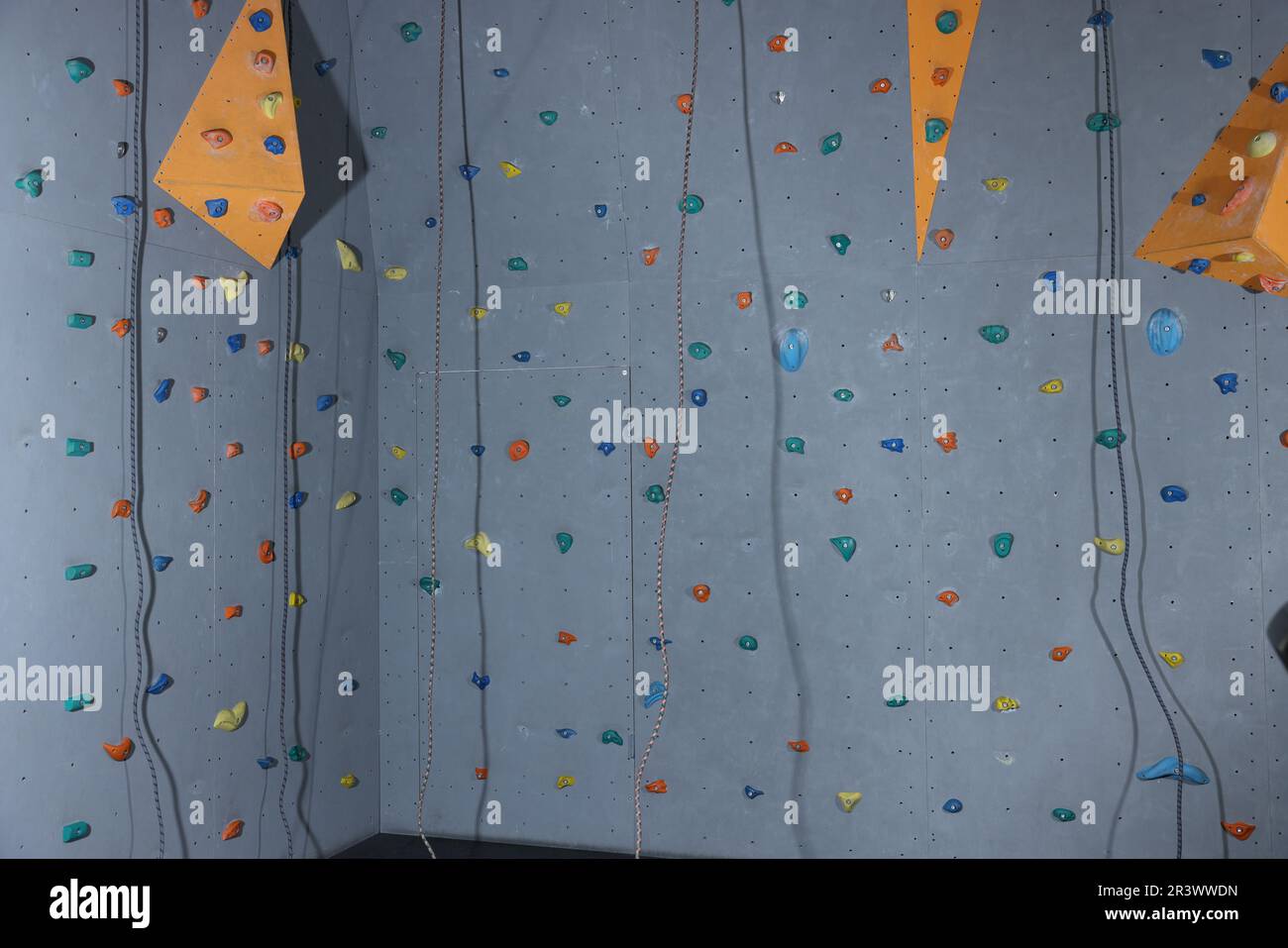 Climbing wall with holds and ropes in gym. Extreme sport Stock Photo ...